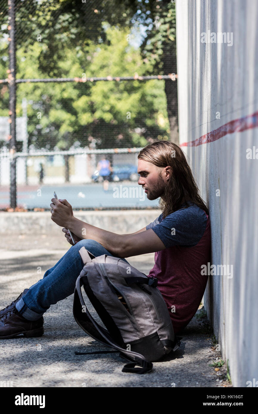 Man sitting down looking at tablet Stock Photo - Alamy