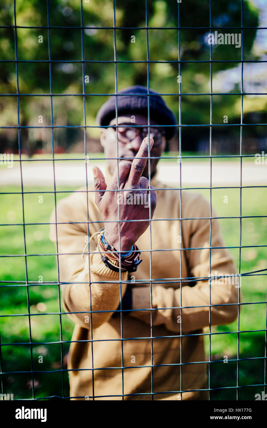 Man behind a metal net giving the finger Stock Photo - Alamy