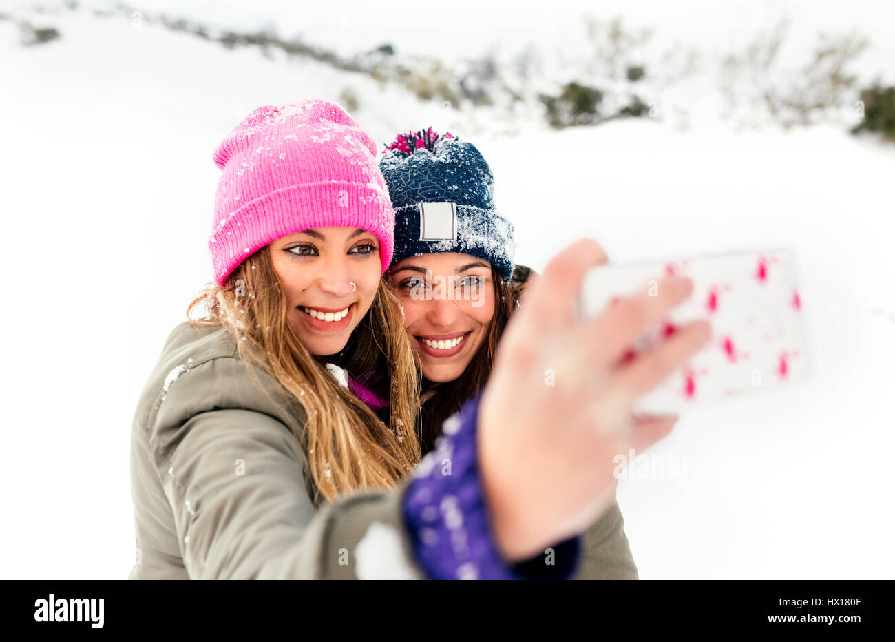 Two friends taking smart phone selfies in the snow Stock Photo - Alamy
