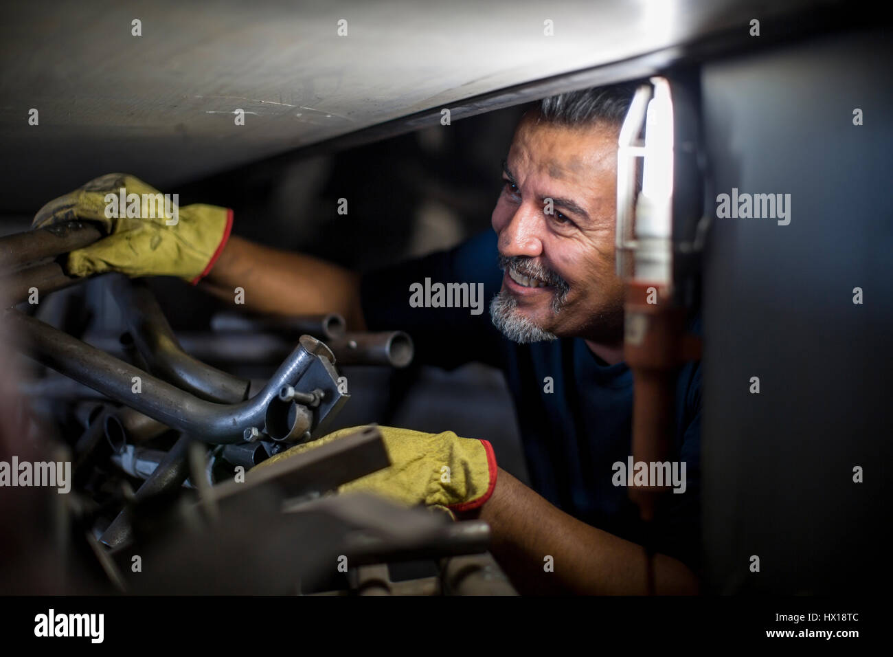 Smiling mechanic working on motorcycle in workshop Stock Photo - Alamy