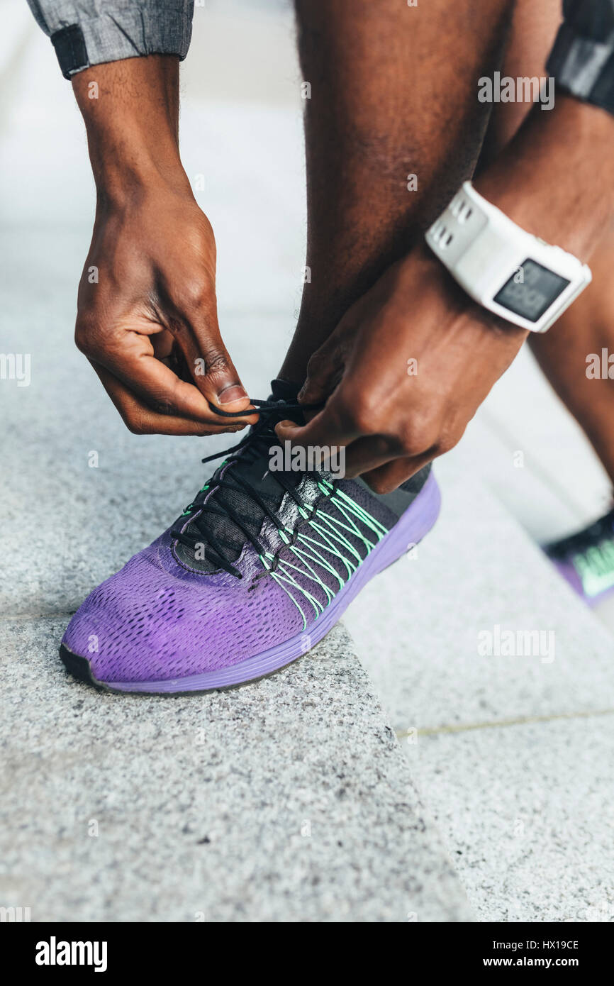 Close-up of athlete wearing smartwatch tying shoes Stock Photo - Alamy