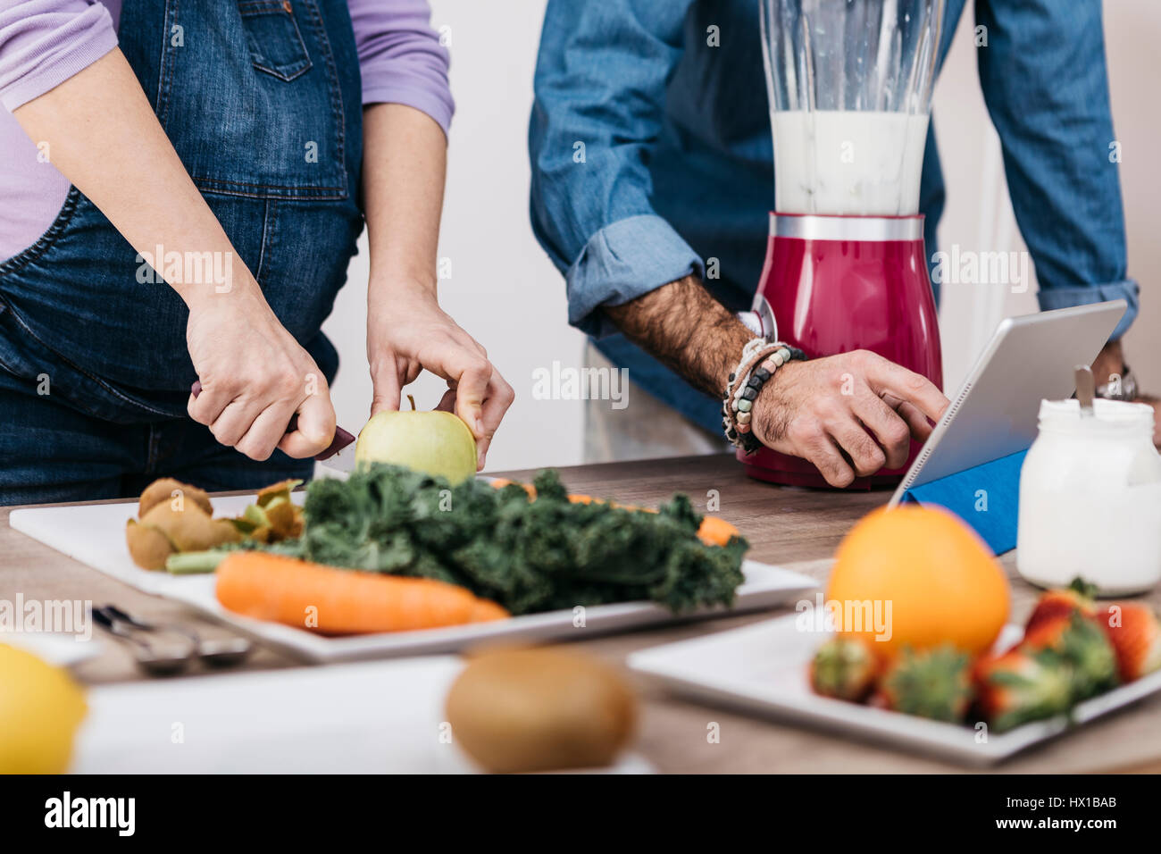 Hands of couple preparing fruits and using tablet for preparing ...