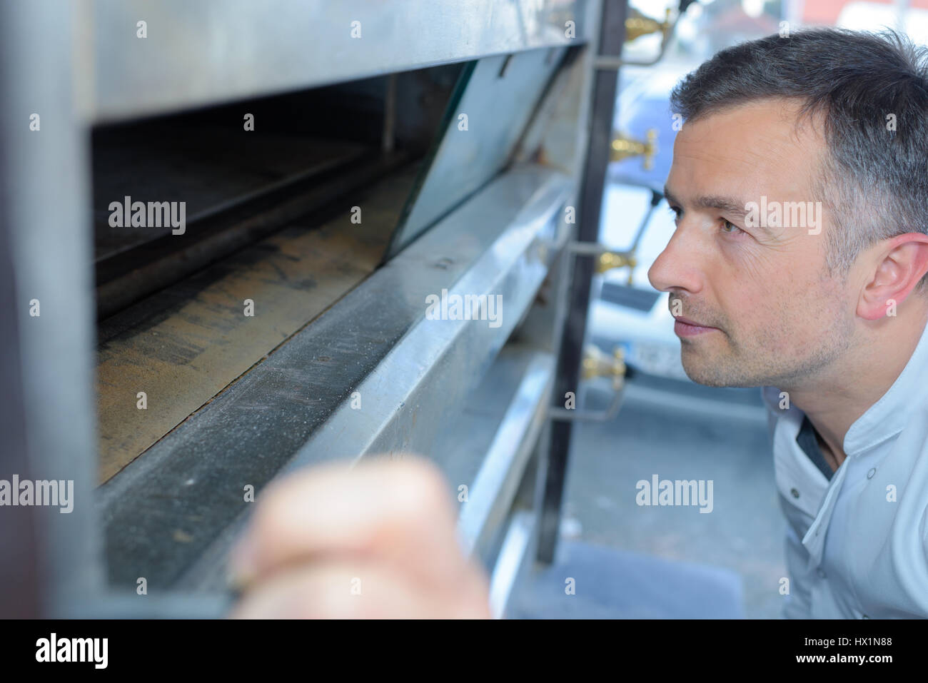 Baker looking in bread oven Stock Photo - Alamy