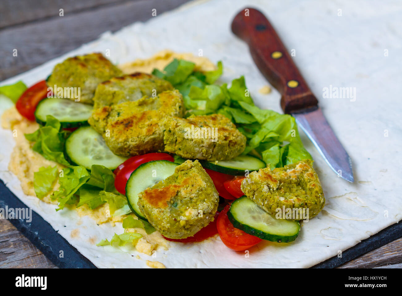 Green open falafel with hummus and vegetables on pita bread on slate ...