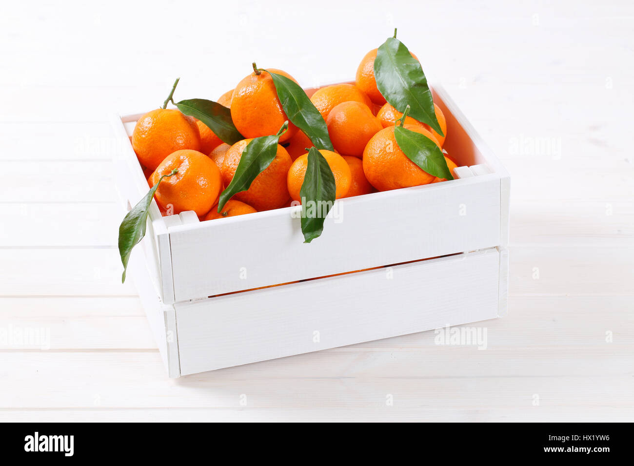 box of fresh tangerines with leaves on white background Stock Photo - Alamy