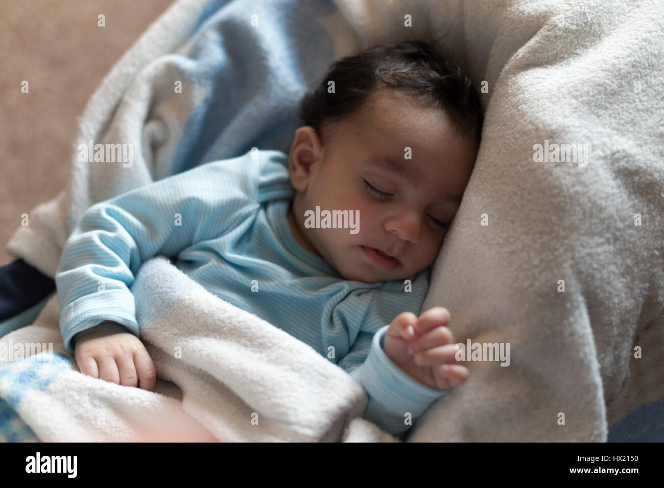 cute, baby boy is fast asleep in his car seat. He is wrapped up in a ...