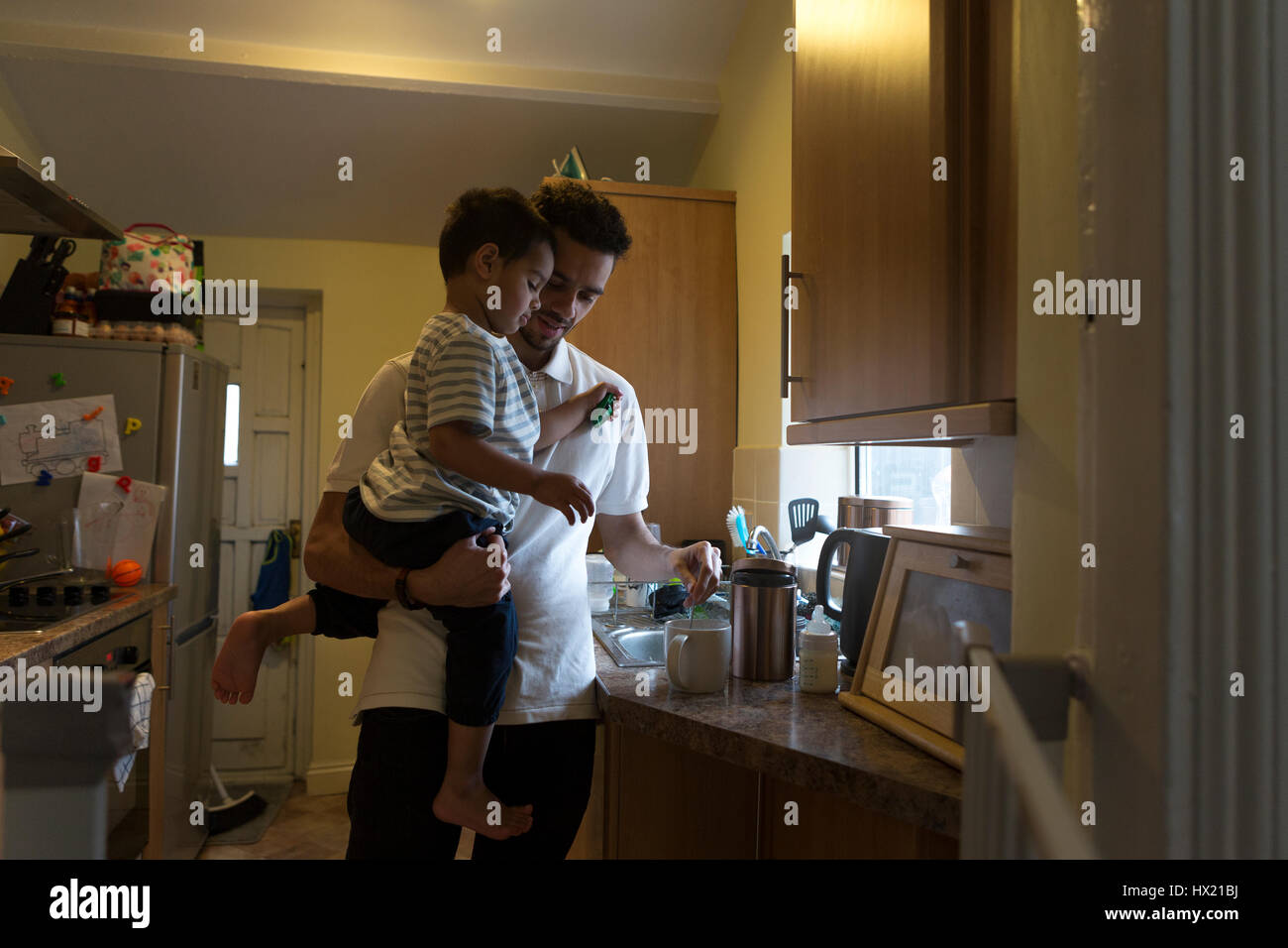 Young father making a cup of tea with his son on his shoulder Stock ...