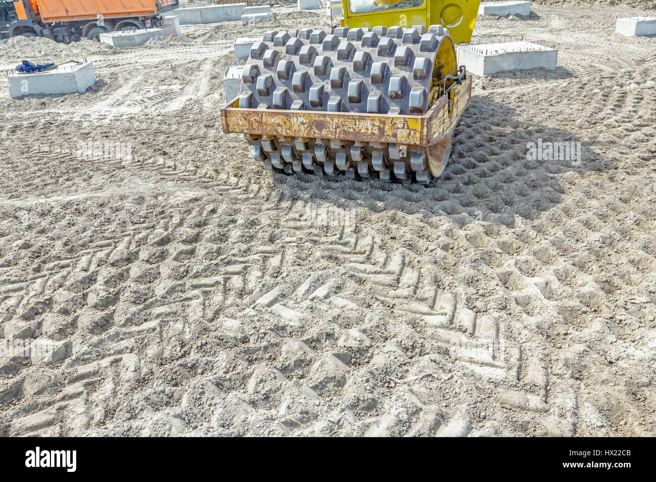 Construction worker is driving huge road roller with spikes and ...