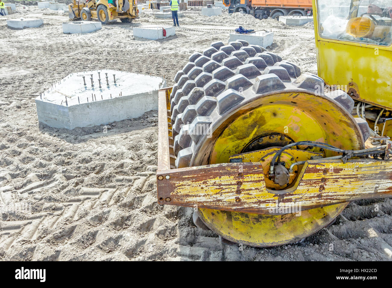 Construction worker is driving huge road roller with spikes and ...