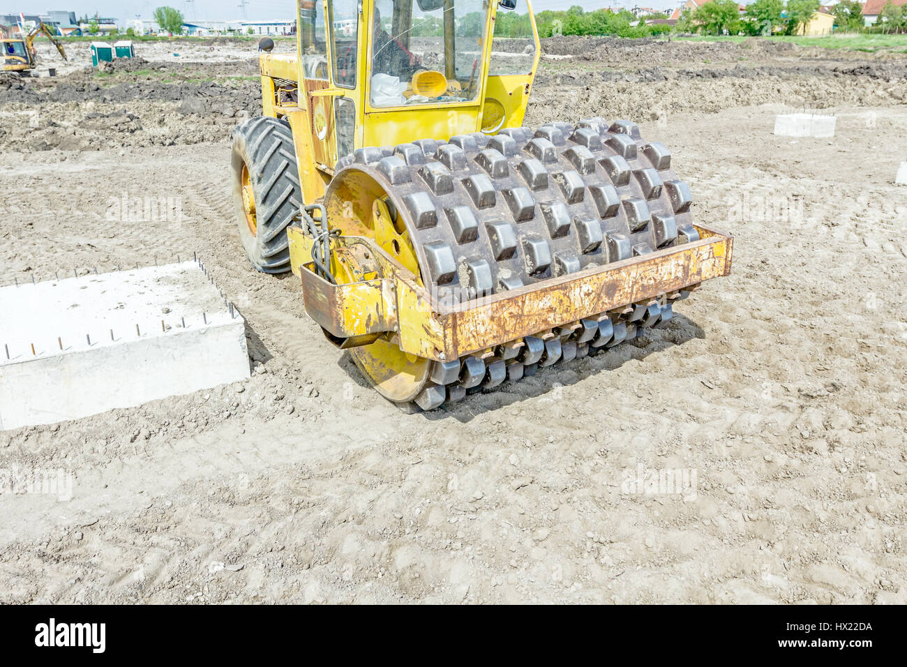 Construction worker is driving huge road roller with spikes and ...