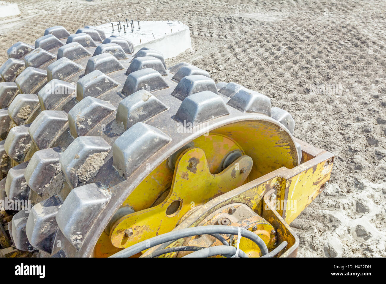 Construction worker is driving huge road roller with spikes and ...
