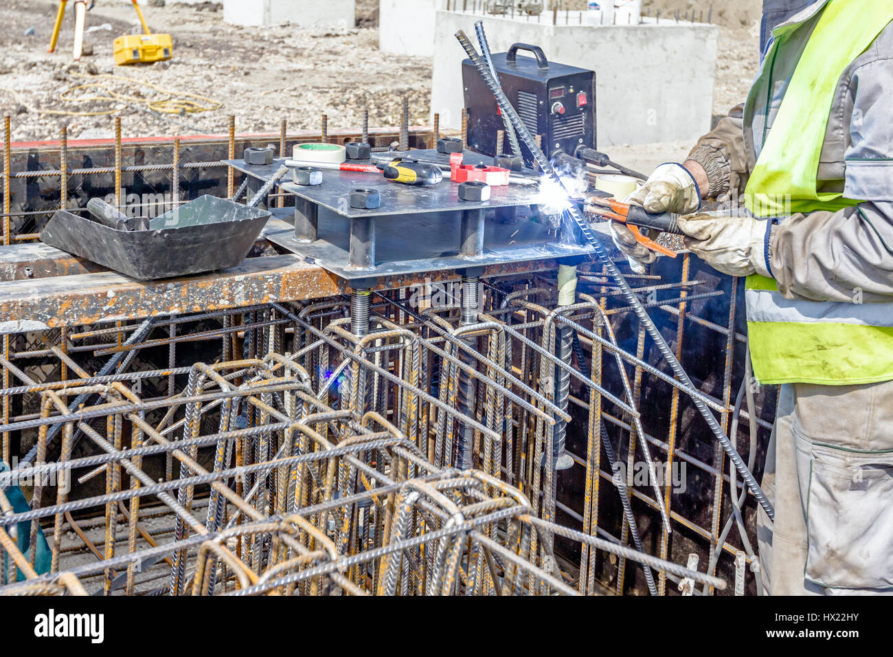 Industrial shot of construction worker who is welding metal frame, cage ...