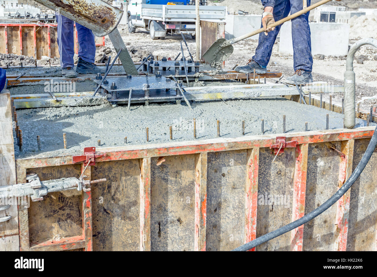 Workers at building site are pouring concrete in mold from mixer truck ...