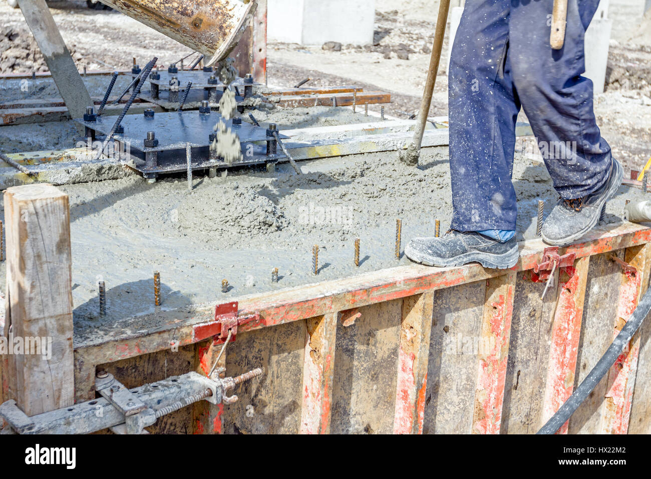 Workers at building site are pouring concrete in mold from mixer truck ...