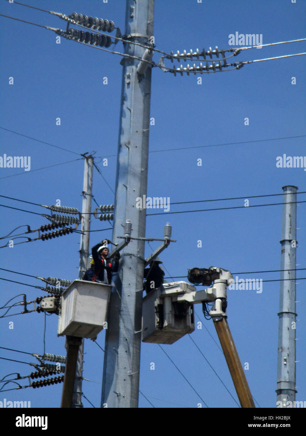 Filipino linemen perform routine maintenance tasks on an electric pole ...