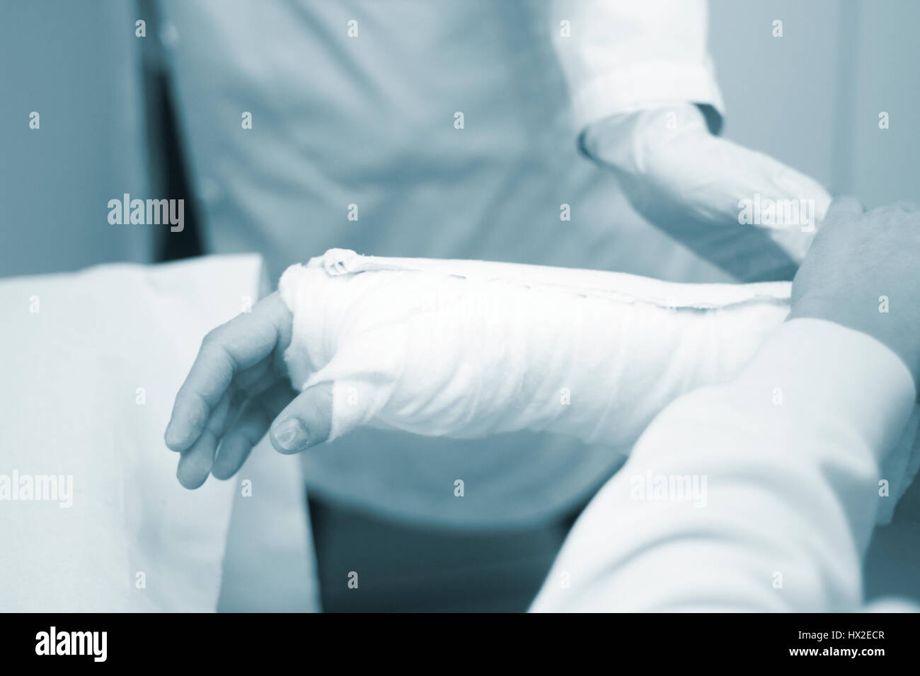 Doctor applying a plaster cast and bandages to patient forearm and ...