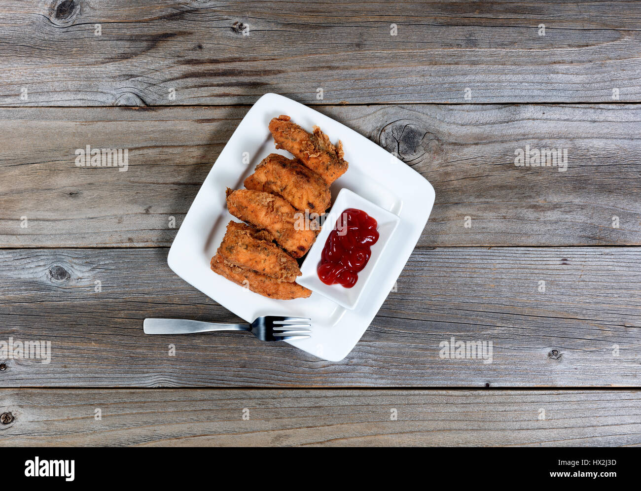 Overhead view of a serving of fried fish plus ketchup on rustic wooden ...