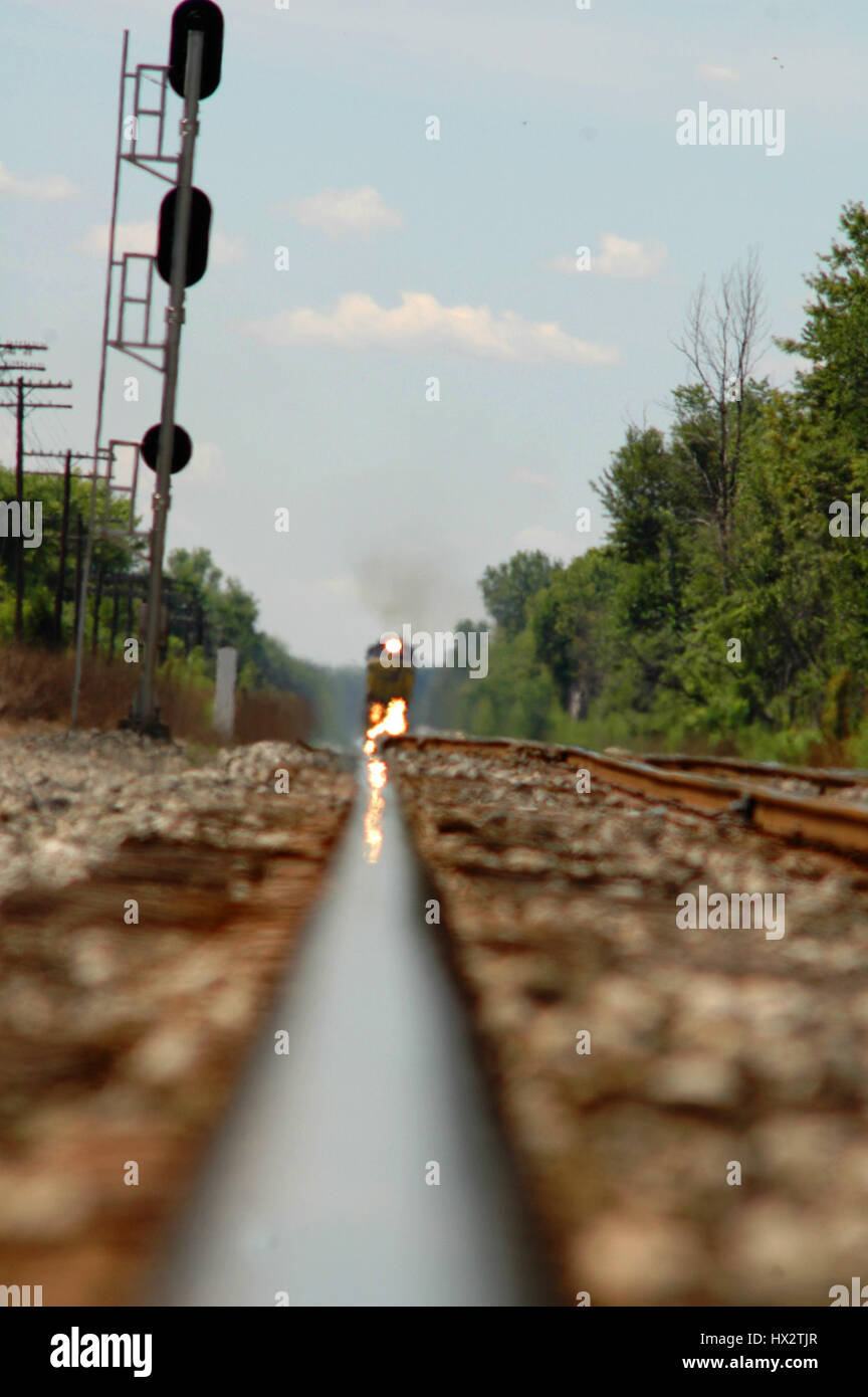 train coming down rail in distance light on vertical Stock Photo - Alamy