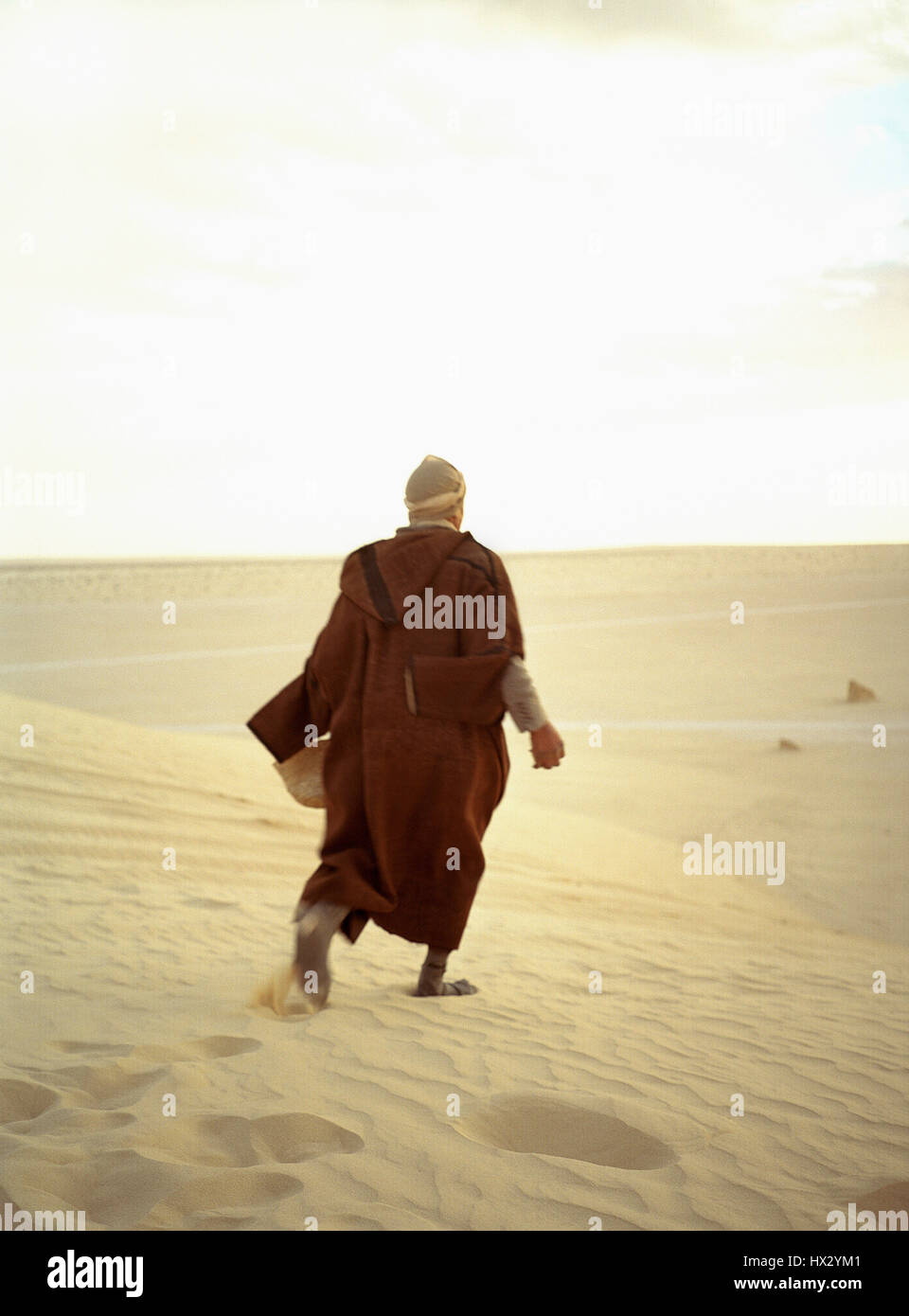 Man in traditional dress walking in the Sahara Desert. Tunisia Stock ...