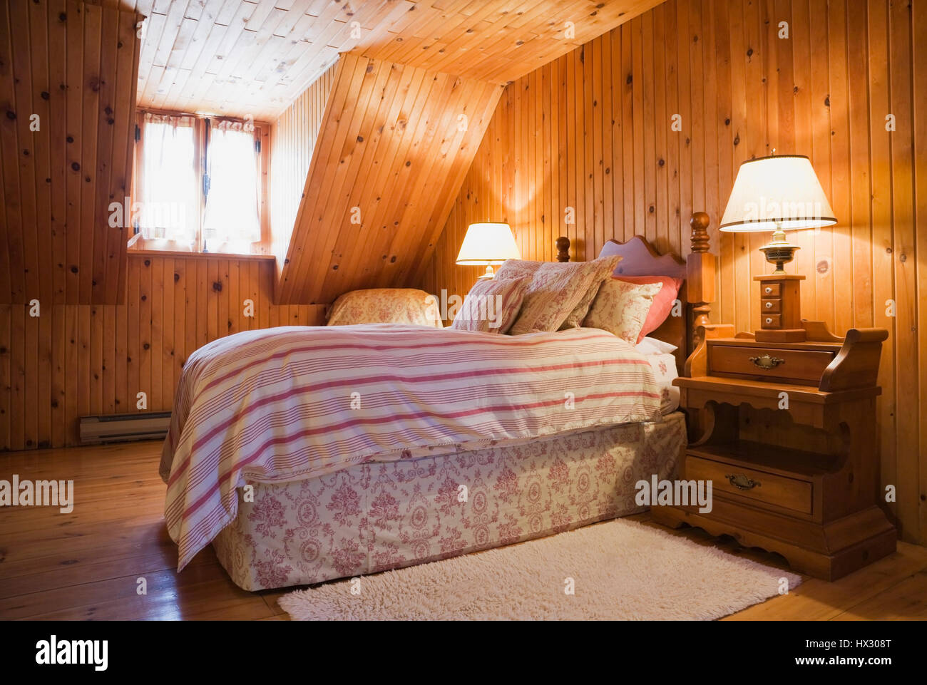 Raised single bed in bedroom with knotted pinewood walls in log home ...
