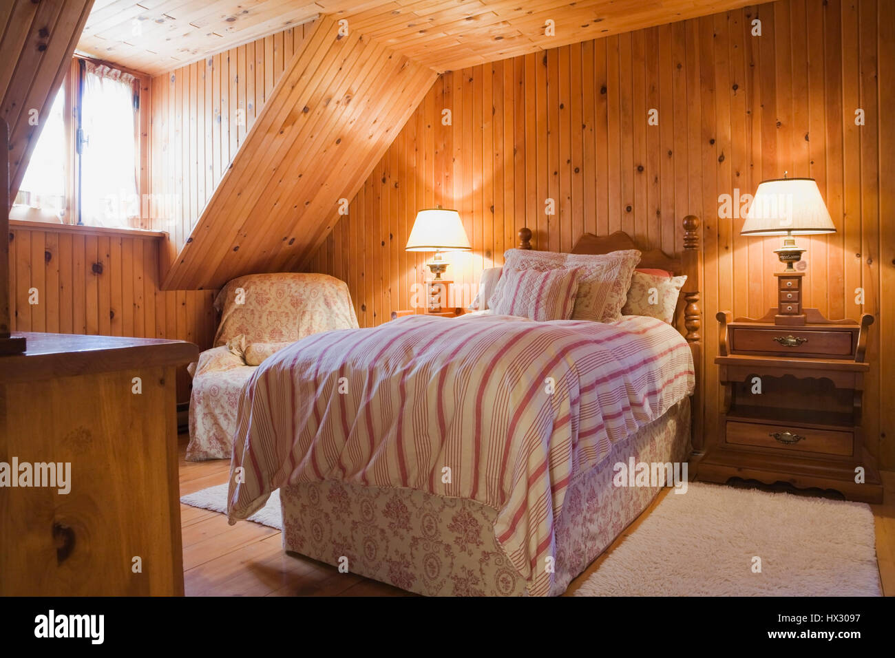 Raised single bed in bedroom with knotted pinewood walls in Canadiana ...