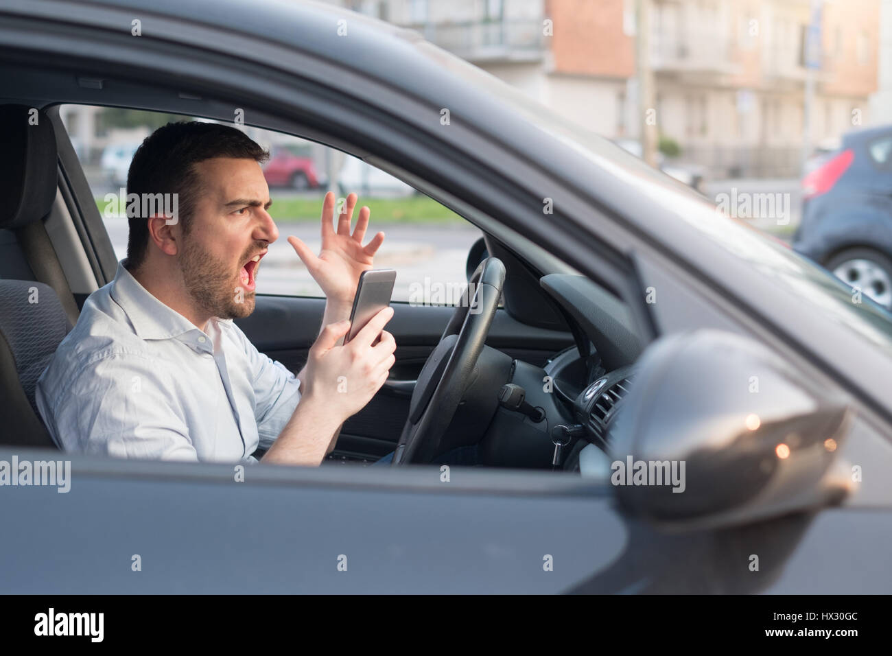 Rude man driving his car and talking on mobile phone Stock Photo - Alamy