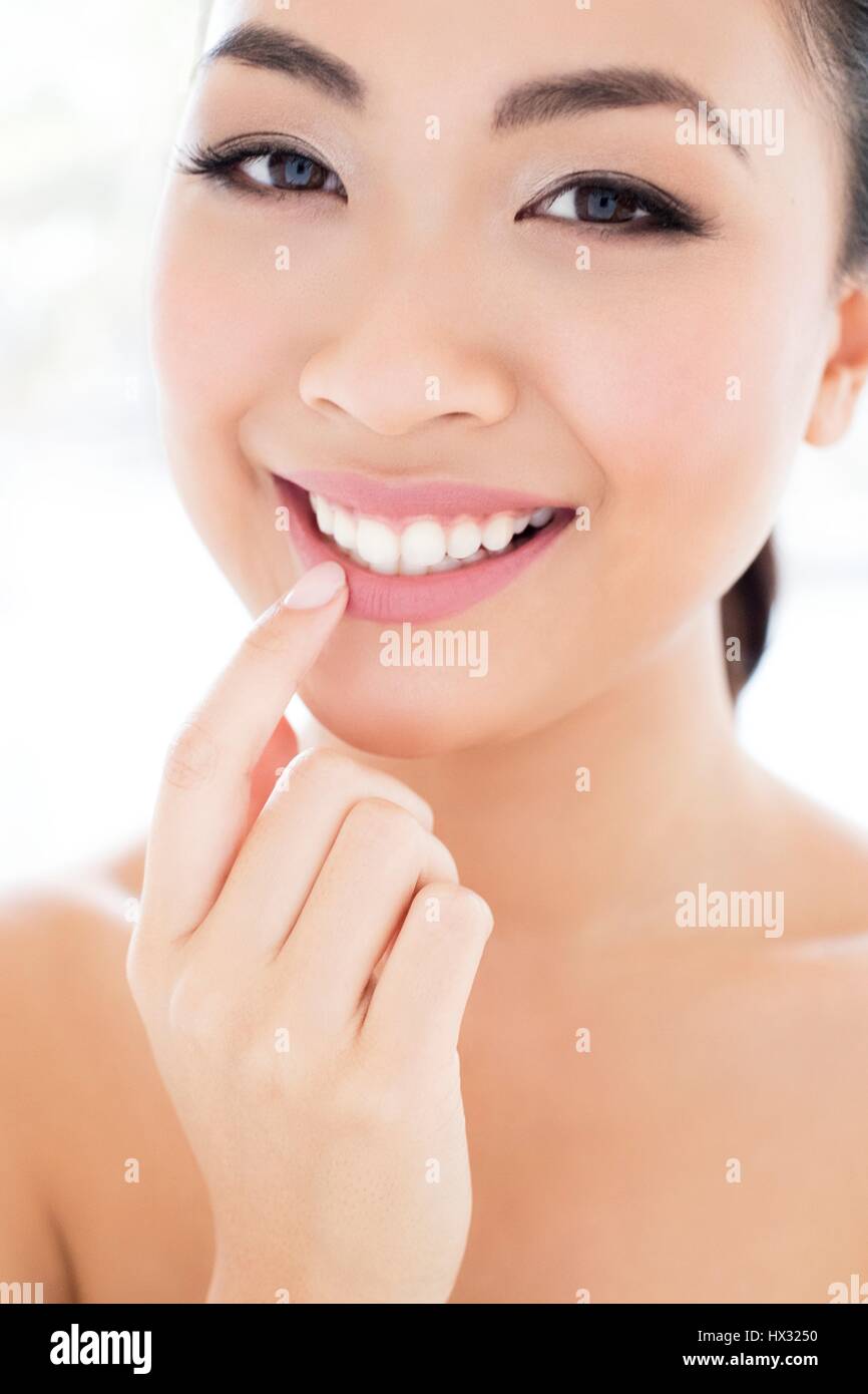 MODEL RELEASED. Young Asian woman touching lip, portrait Stock Photo ...