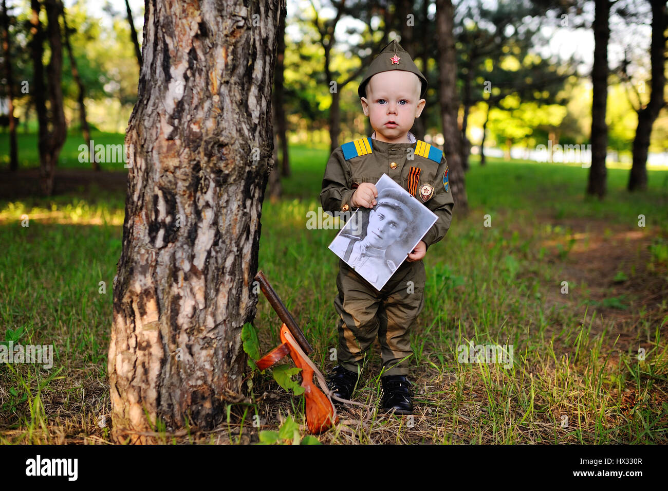 Child boy in military uniform of a Soviet soldier with a photograph of ...