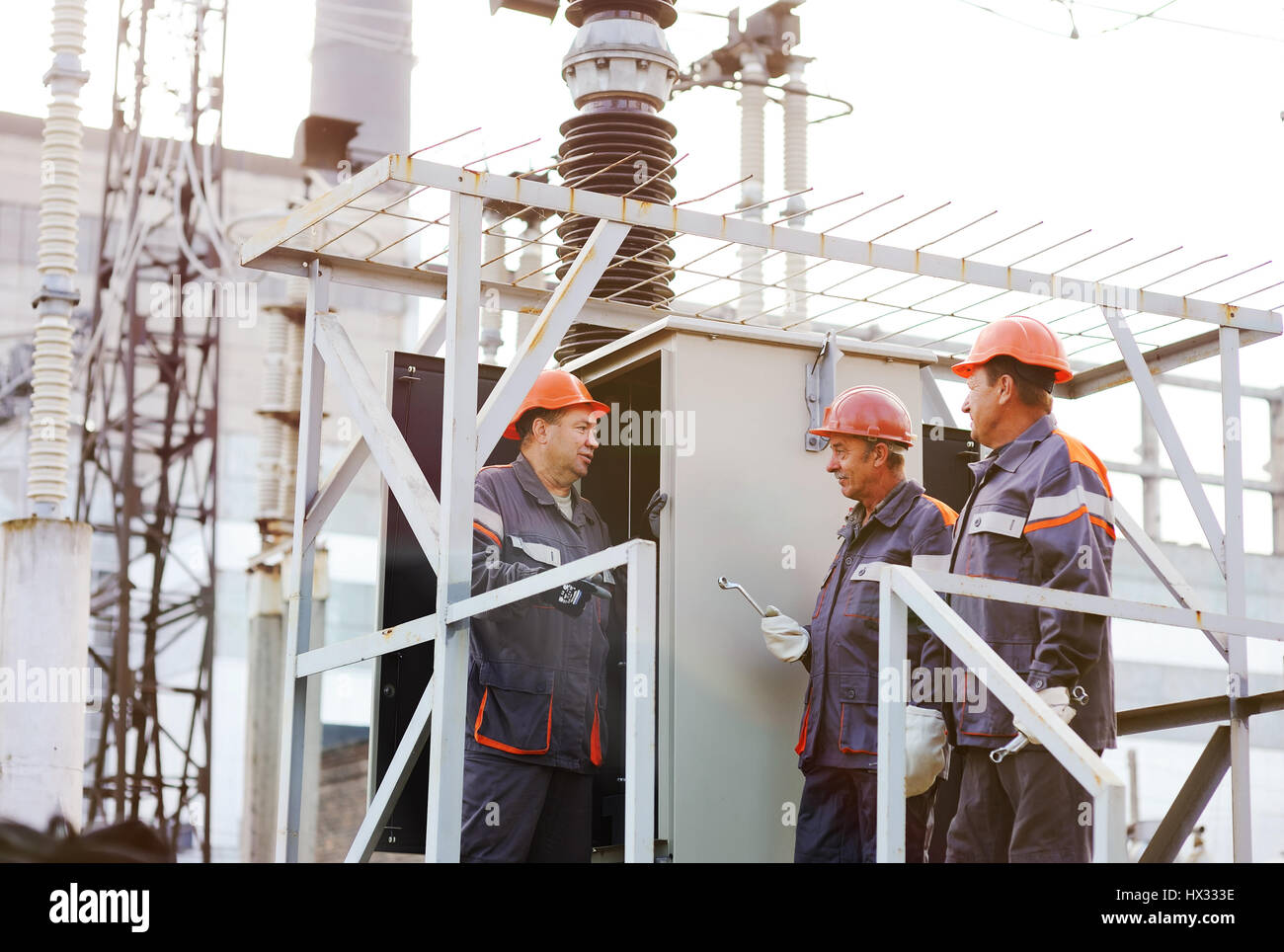 Electrical workers repair the power plant on the background of ...