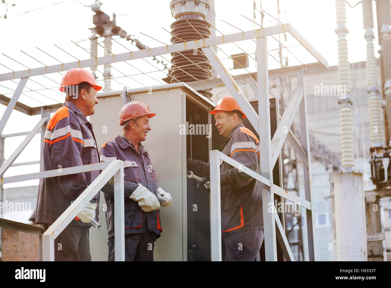 Electrical workers repair the power plant on the background of ...