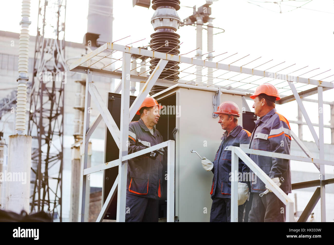 Three electrical workers discuss the problem and repair the electrical ...