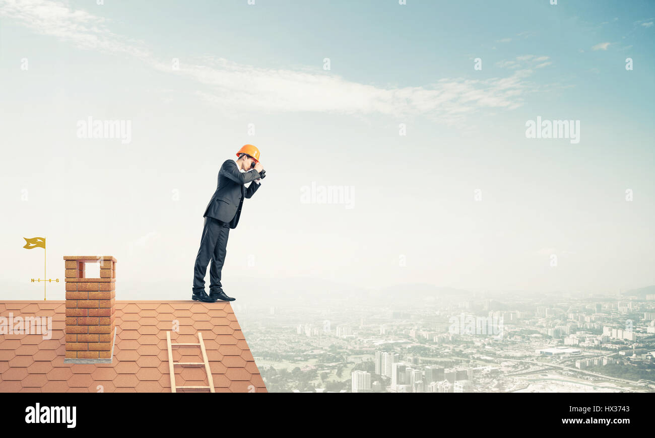 Engineer man standing on roof and looking in binoculars. Mixed m Stock ...