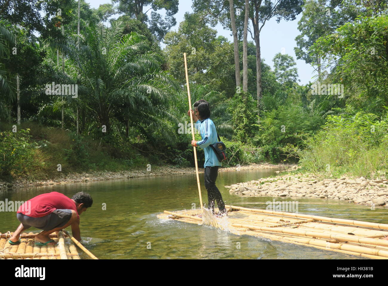 Man, standing and squating on bamboo raft, with bamboo stick in his ...