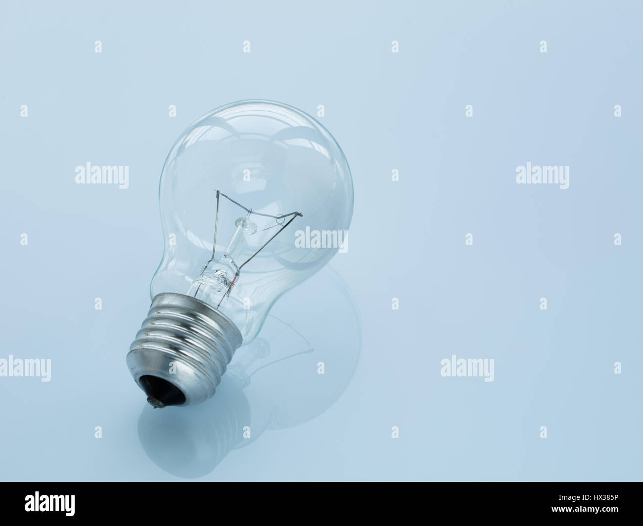 The light bulb lies on a glossy surface on a light blue background ...