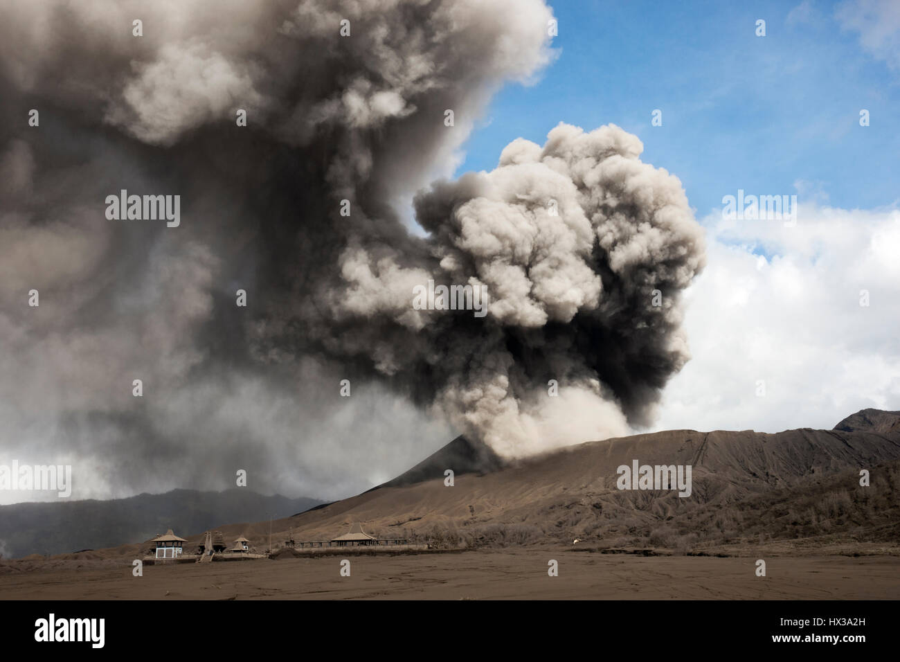 Grey smoke coming out of an active volcano filling the sky at the ...