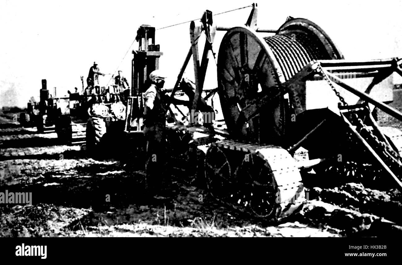 Workers use a plow train to lay six strands of coaxial cable for a ...