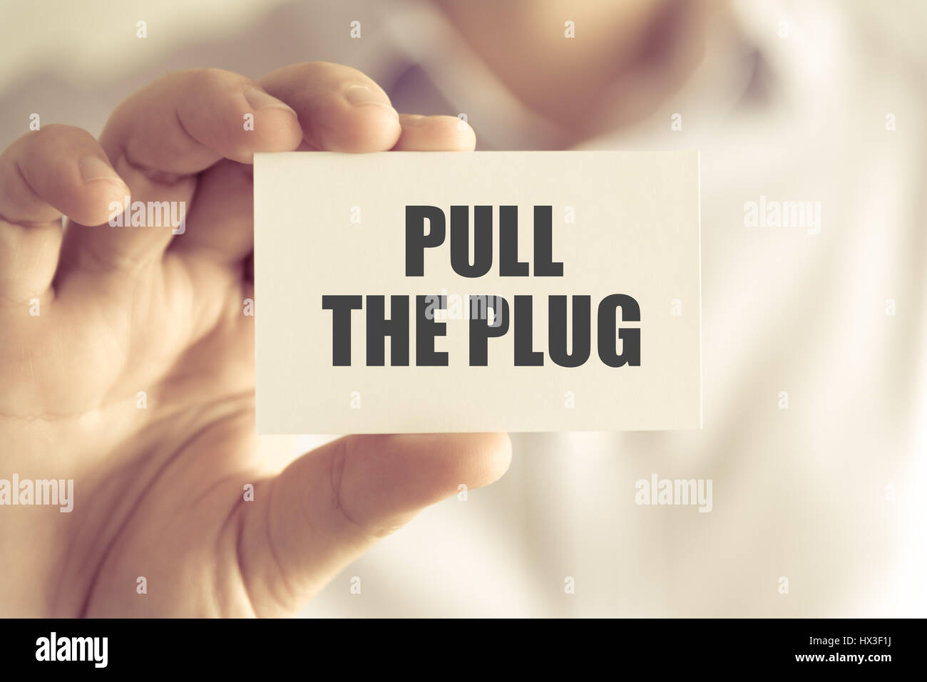 Closeup on businessman holding a card with text PULL THE PLUG, business ...