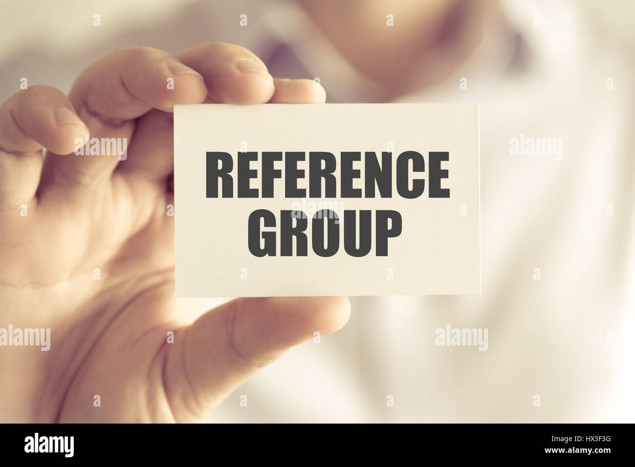 Closeup on businessman holding a card with text REFERENCE GROUP ...