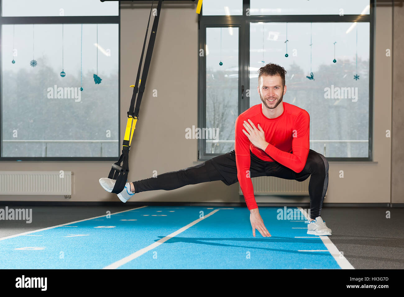 white curly bearded sporty man exercising with fitness straps in gym ...