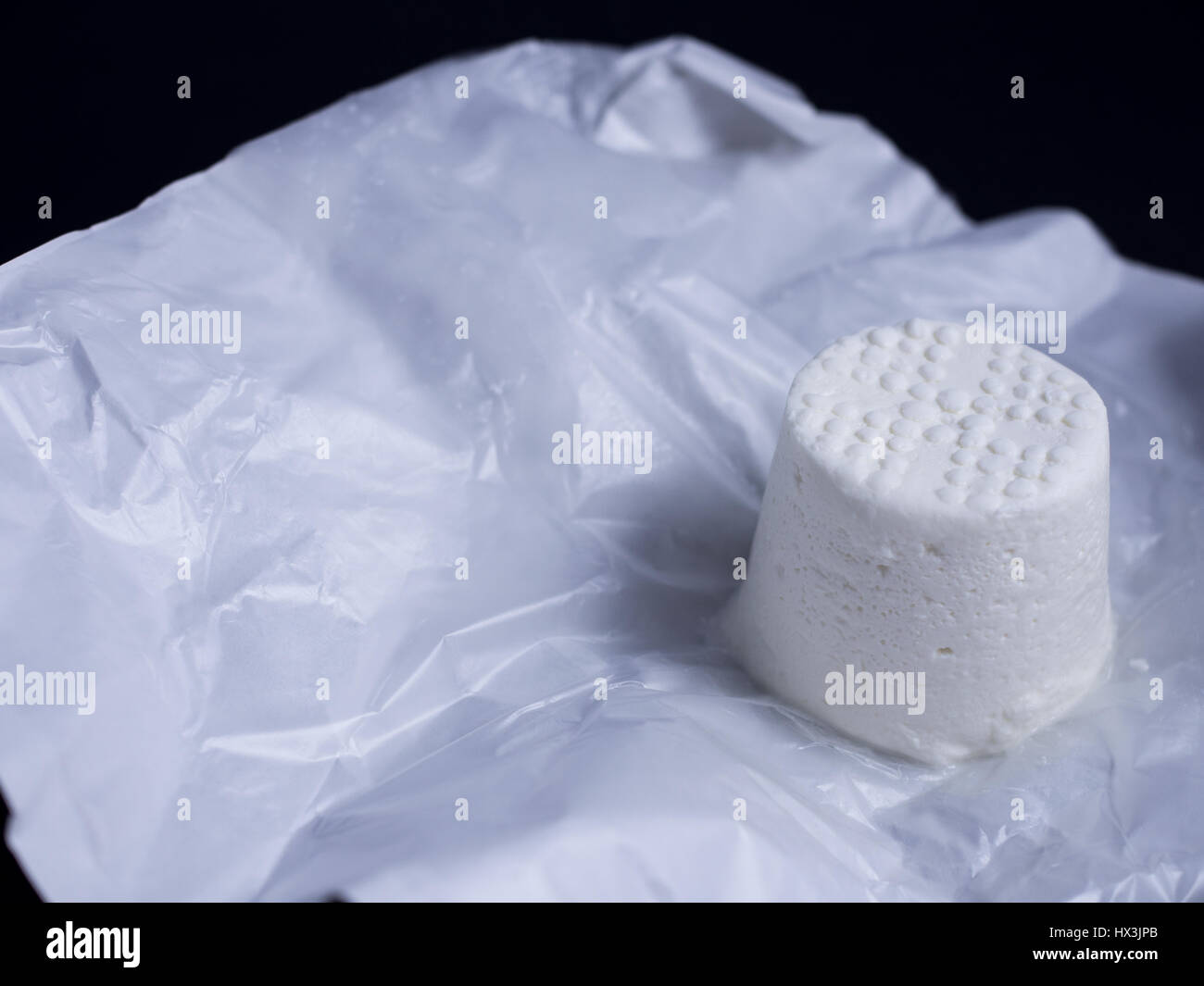 Cylinder formed fresh goat cheese on white paper isolated on black ...