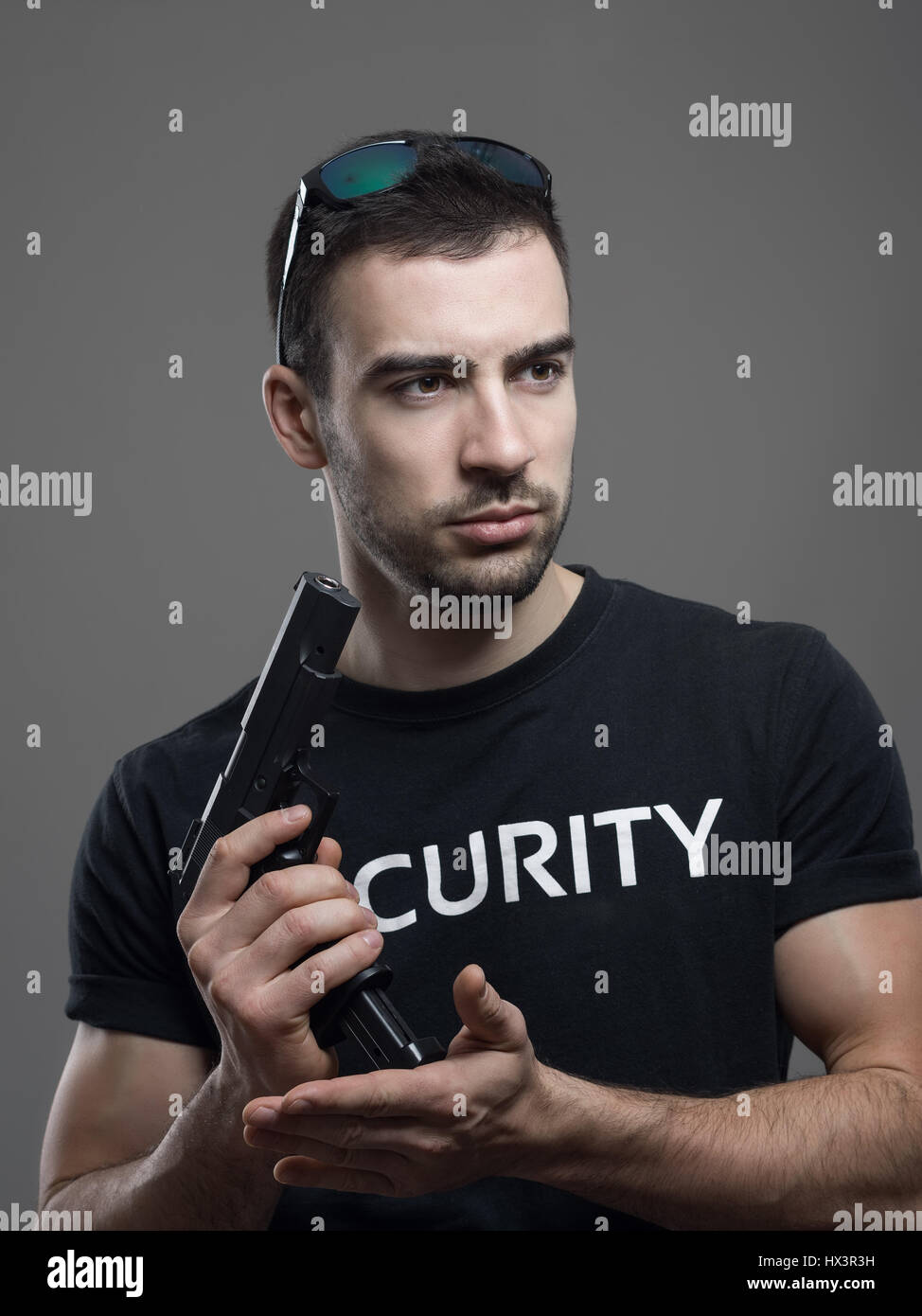 Confident touch macho security guard reloading gun looking away ...