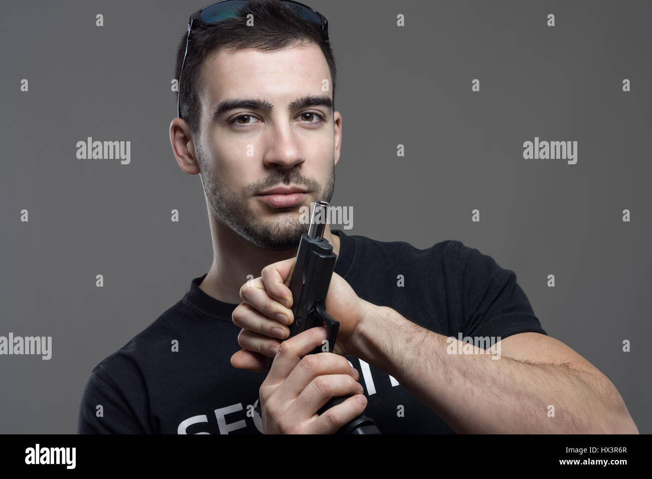 Cool security agent cocking and reloading handgun looking at camera ...