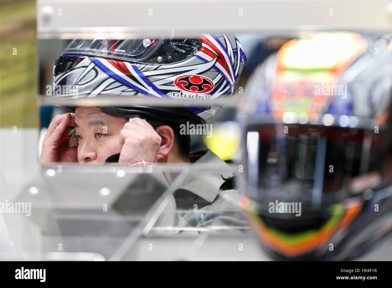 A visitor tries a motorcycle helmet on display during the 44th Tokyo ...