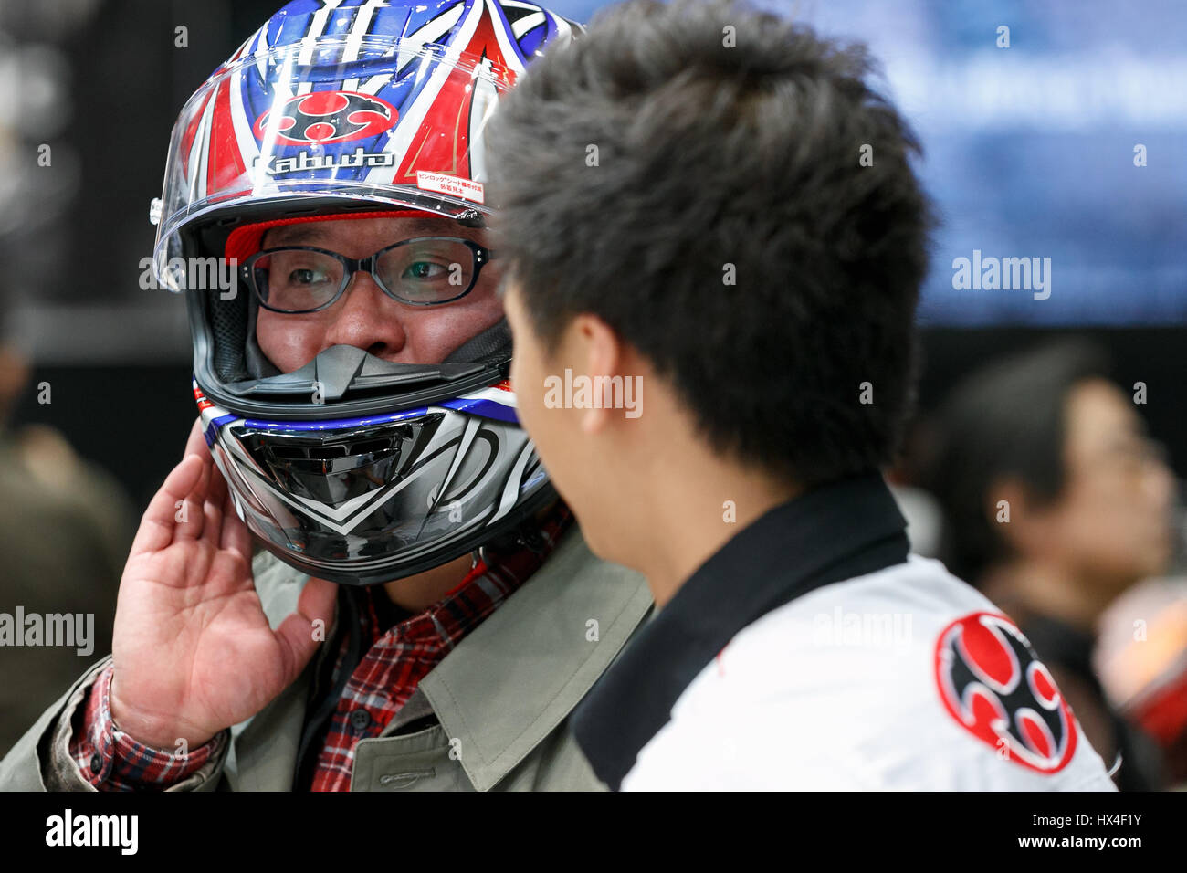 A visitor tries a motorcycle helmet on display during the 44th Tokyo ...