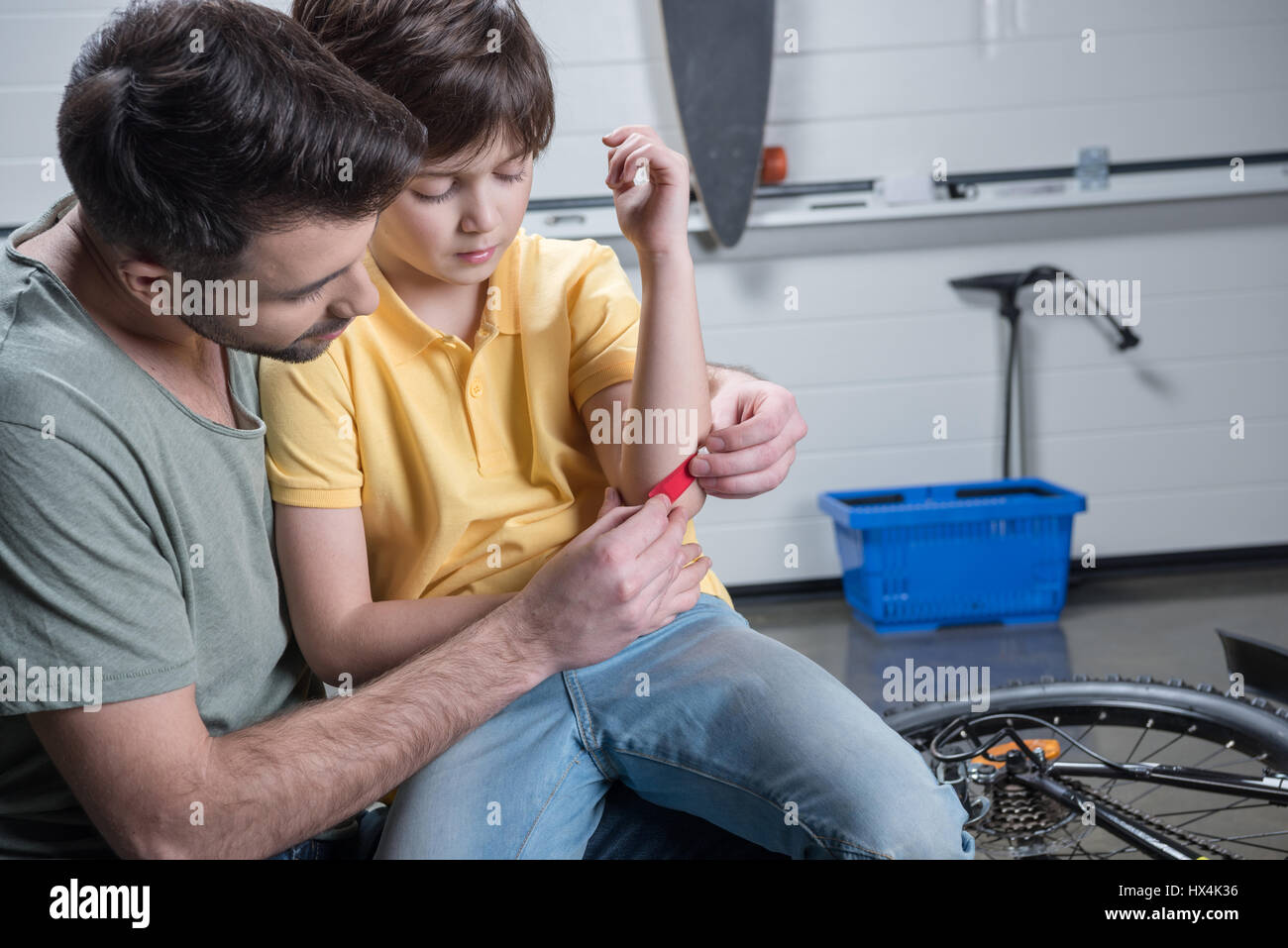 Father putting medical patch on elbow of son falling off bike Stock ...