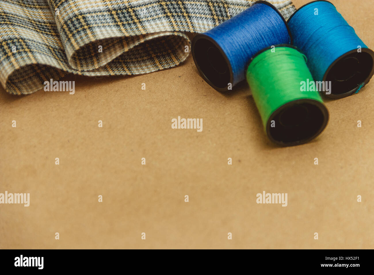 Cotton thread bobbins and cloth on paper craft with copyspace, sewing ...