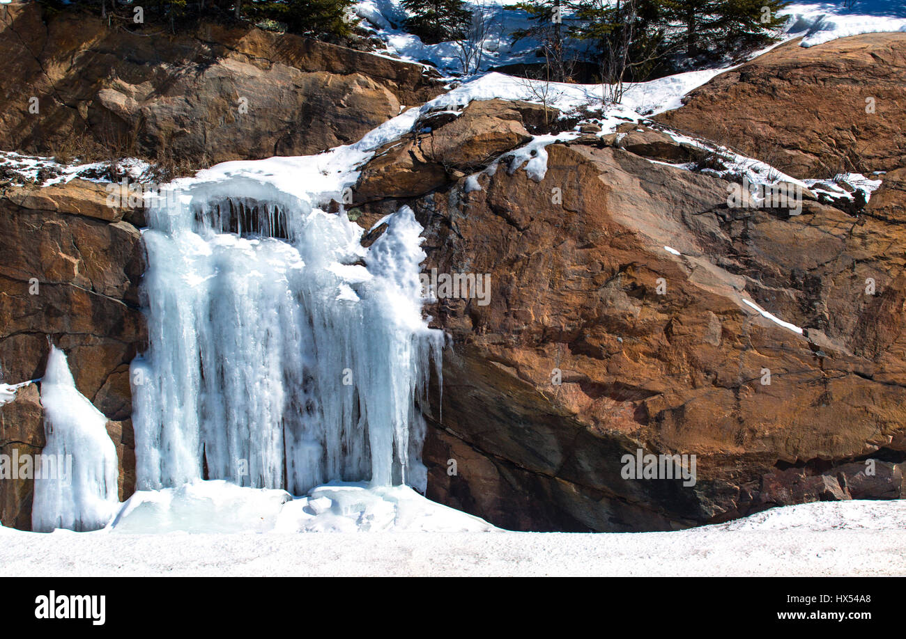 Natural stone rock face with ice from runoff Stock Photo - Alamy