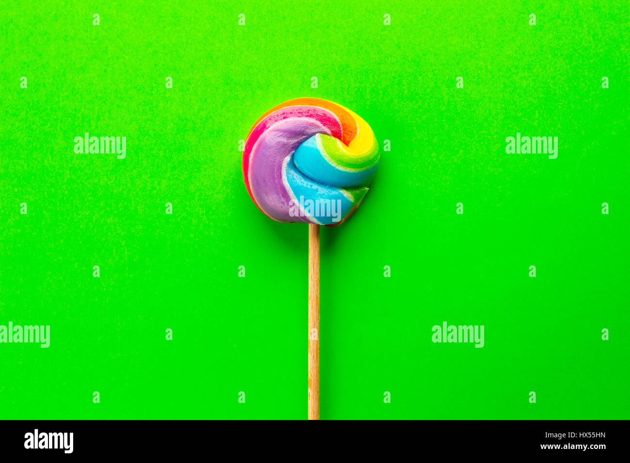 rainbow colored lollipop isolated on green background. copy space Stock ...