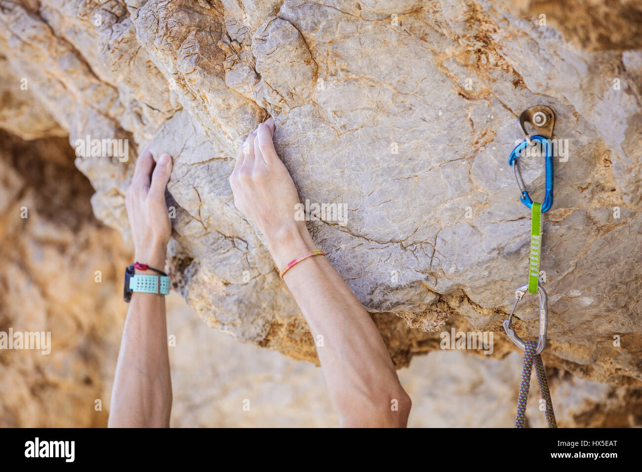 Closeup of climber's hands on cliff beside bolt with clipped quickdraw ...