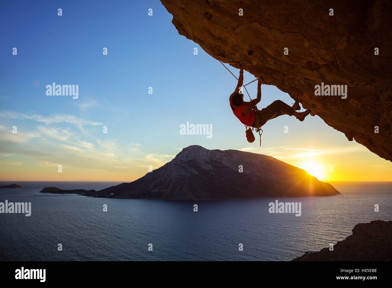 Young man climbing overhanging cliff at sunset, Kalymnos island, Greece ...